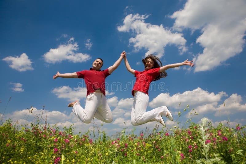 Happy Young Love Couple - Jumping Stock Image - Image of grass, clouds ...