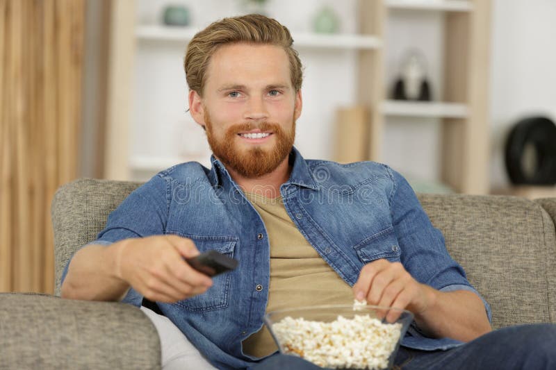 Happy Young Man Eating Popcorn while Sitting on Couch Stock Image ...