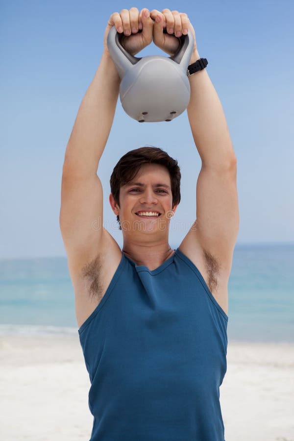 Happy Young Man Lifting Kettlebell at Beach Stock Image - Image of sand ...