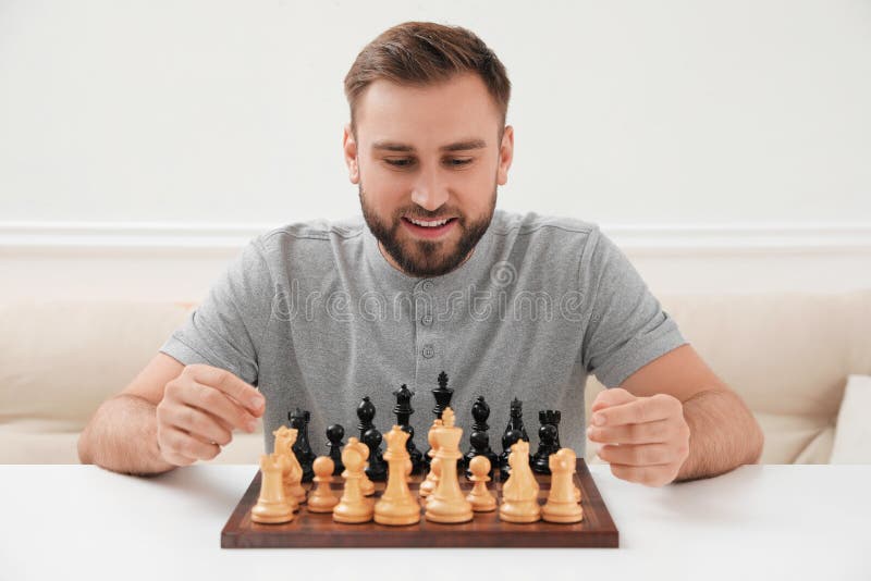 Happy Young Man Playing Chess at White Table Indoors Stock Image ...