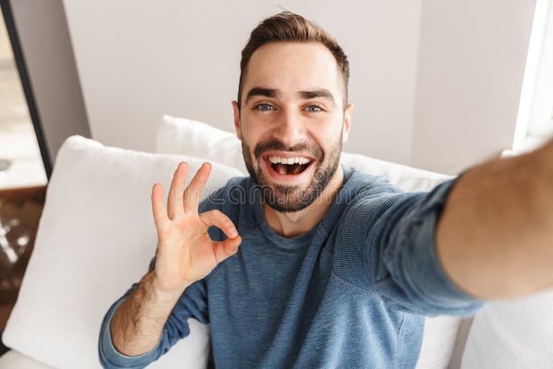 Happy Young Man Sitting on a Couch at Home Stock Photo - Image of ...