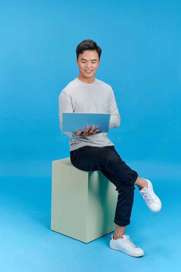 Happy Young Man Sitting on Mint Color Cube and Using Laptop Stock Photo ...