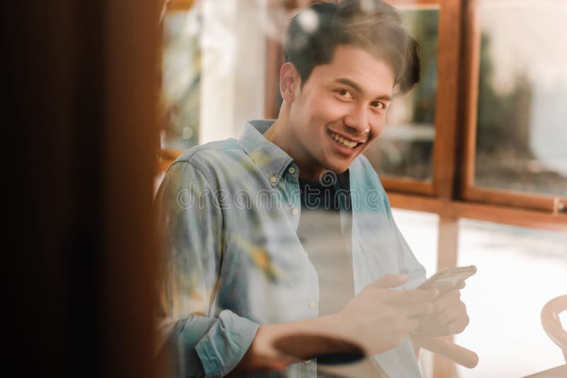 Happy Young Man Smiling and Looking at Camera through Glass Window ...