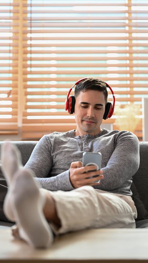 Happy Man Wearing Headphone and Using Smart Phone on Sofa. Stock Image ...