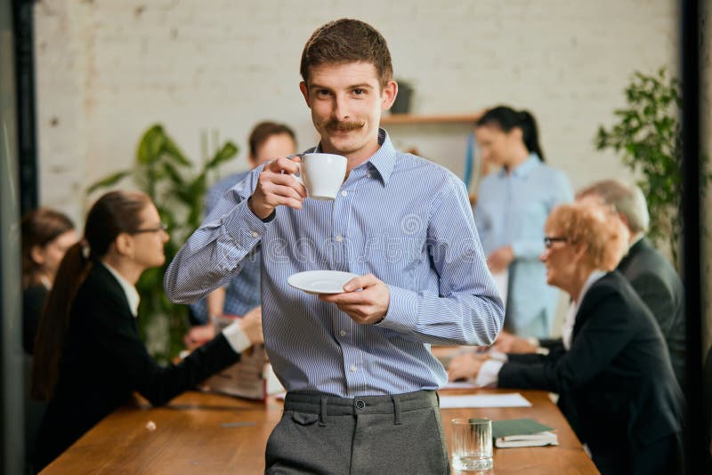 Happy Young Manager Looking at Camera and Drinking Coffee. Work in ...