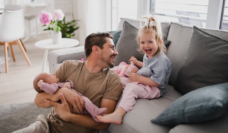 Happy Young Man Taking Care of His Newborn Baby and Little Daughter ... Happy Young Man Taking Care of His Newborn Baby and Little Daughter ...