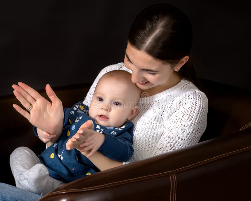 Happy Young Mother With Her Daughter On Her Hands On A Black Bac Stock