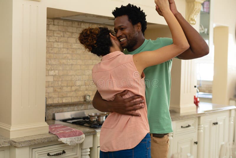 Happy Young Multiracial Couple Dancing While Hugging Each Other In