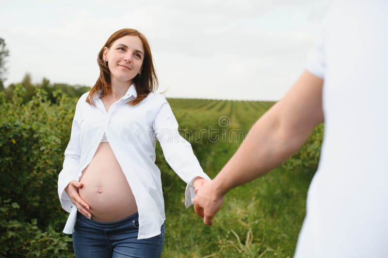 Happy And Young Pregnant Couple Hugging In Nature Stock Image Image