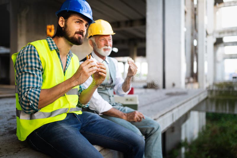 Happy Young and Senior Engineer Worker Sitting at Building Site on ...