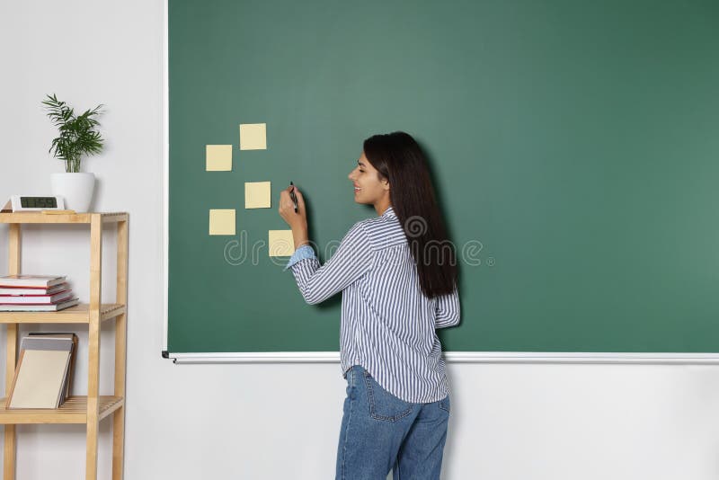 Happy Young Teacher Giving Lesson at Blackboard in Classroom. Space for ...
