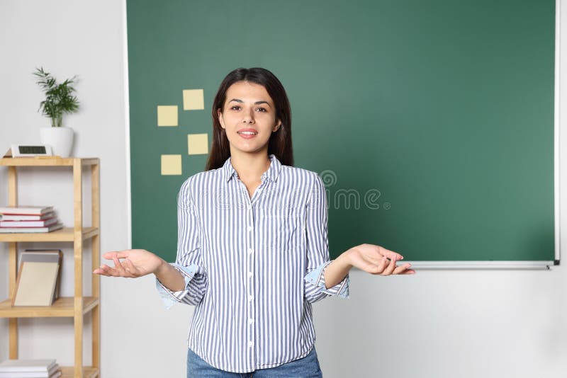 Happy Young Teacher Giving Lesson at Blackboard in Classroom. Space for ...
