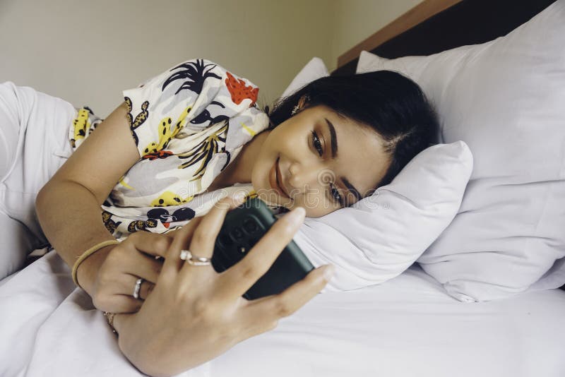 Happy Young Woman Checking on Her Phone while Lying in Bed Stock Image ...
