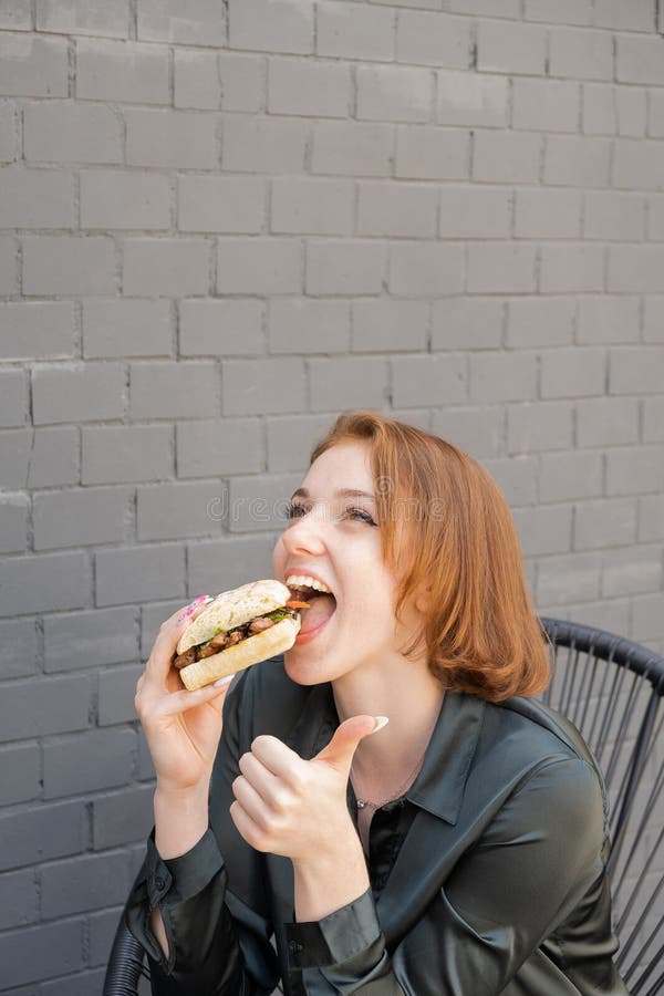 A Young Woman Eats a Burger with Meat on a Summer Terrace Stock Image ...