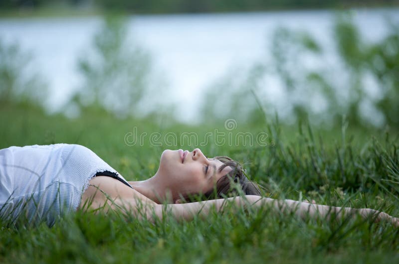 Young Woman Lying on the Field in Green Grass and Blowing Dandelion ...