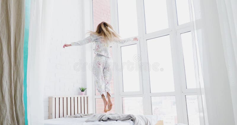 Happy, Young Woman Dancing, Jumping on Bed at Home and Singing Using ...