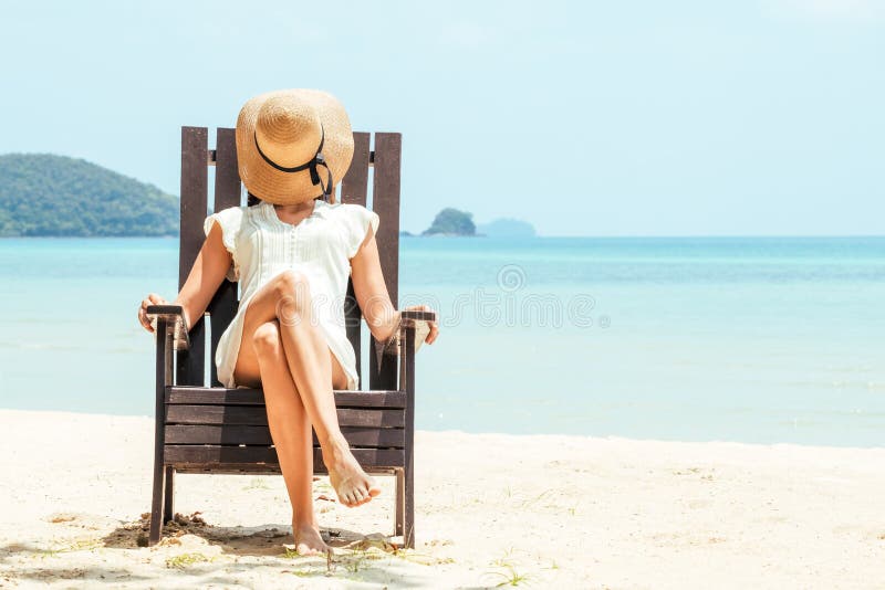 Happy Young Woman Sitting On Beach Chair On Tropical Beach In White