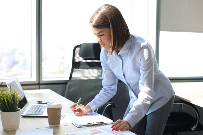 Happy Young Woman Writing Something Down while Working in the Office ...