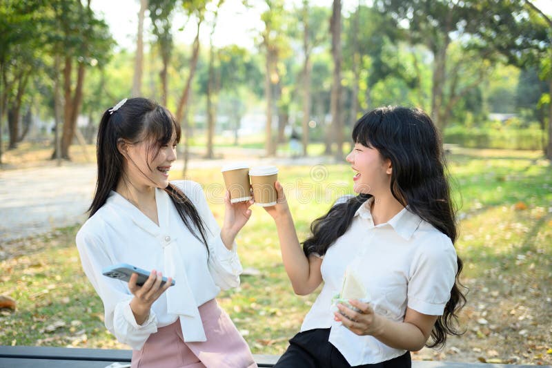 Happy Young Women Office Workers Sitting on Park Bench and Drinking ...