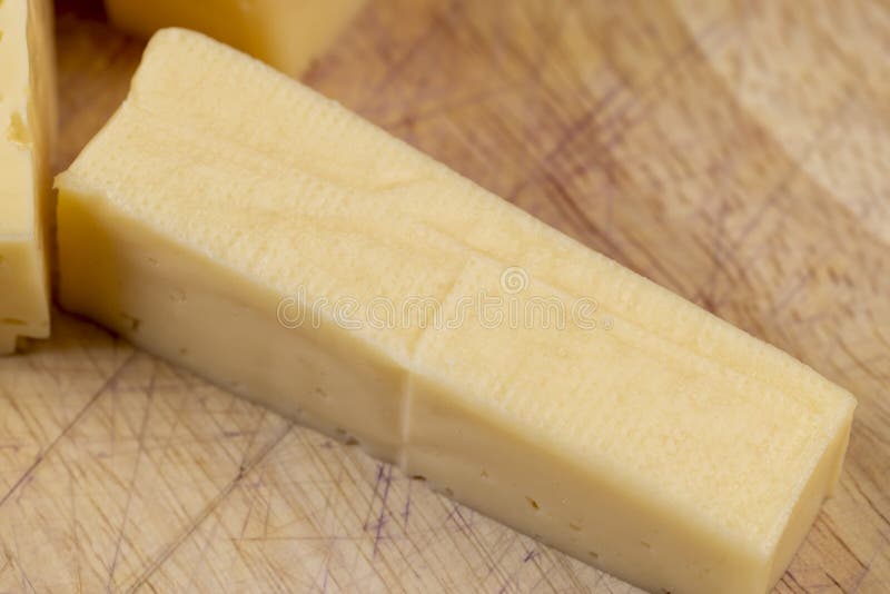 Hard Cheese with Holes Cut into Thick Pieces on a Cutting Board Stock ...