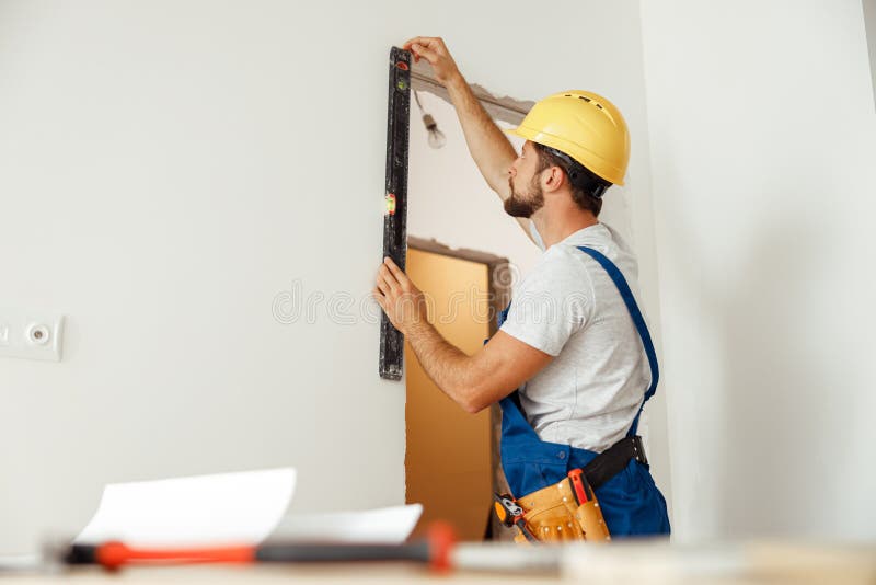 Hard Working Handyman, Builder in Uniform Measuring the Wall Using ...
