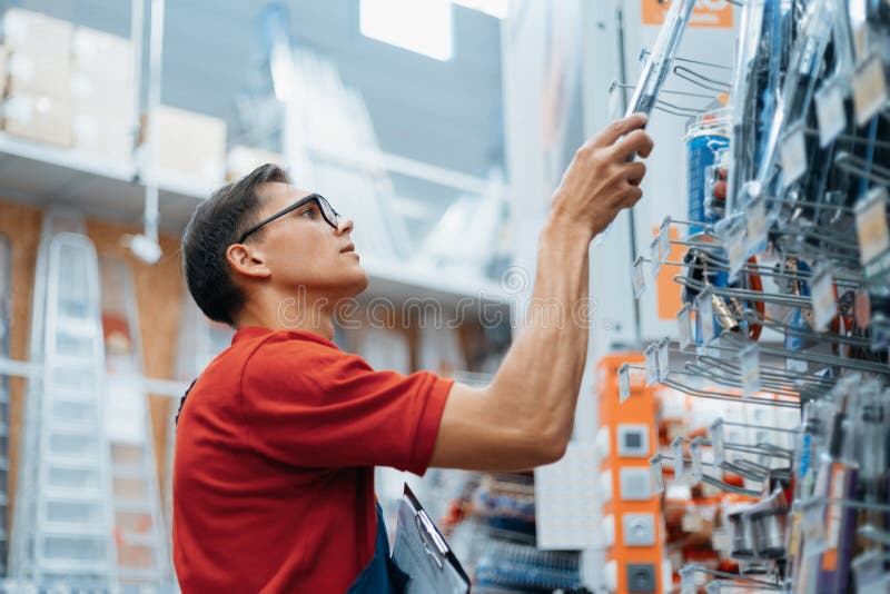 Hardware Store Clerk Looking at a Rack of Tools. Stock Photo - Image of ...