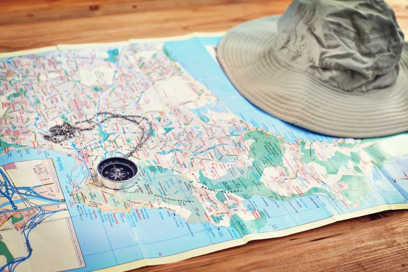 Hat, Map and Travel Guide with Compass on Table for Itinerary Schedule ...