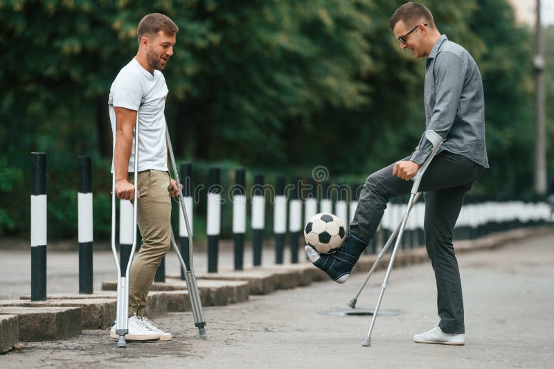 Having Fun, Playing Soccer. Two Men with Crutches is Outdoors on the ...