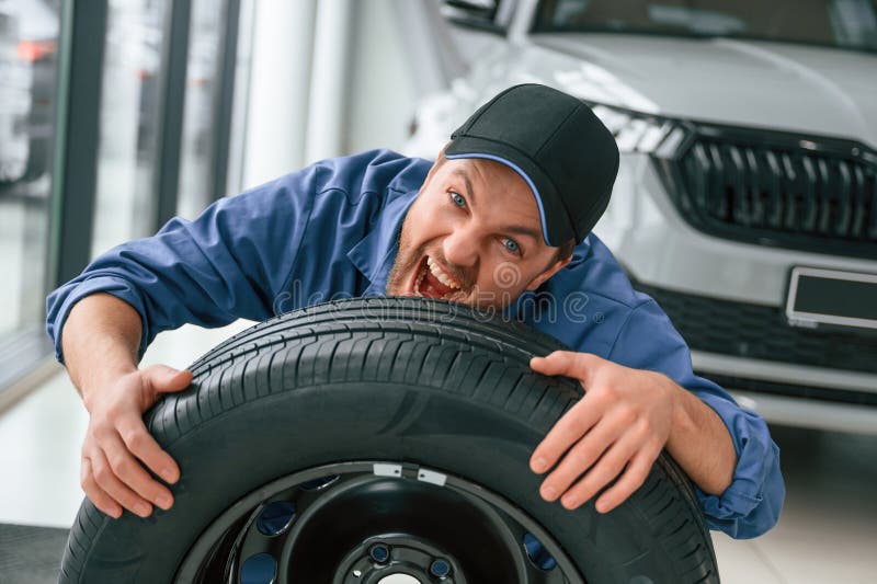 Having Fun, Smiling, with Tire. Man in Blue Uniform is Working in the ...