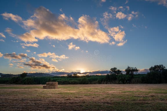 Hay on a Field during a Sunset with Clouds and the Sun Stock Image ...