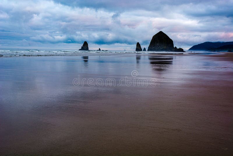 Haystack Rock on Cannon Beach Under Cloudy Dusk Sky, Oregon Stock Image ...