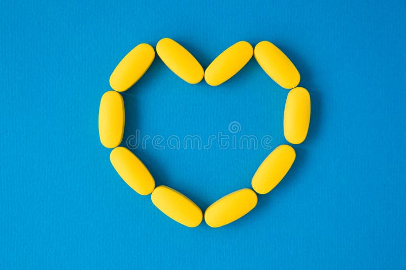 Health Protect Concept of Yellow Pills Tablets in Heart Shape on Blue ...