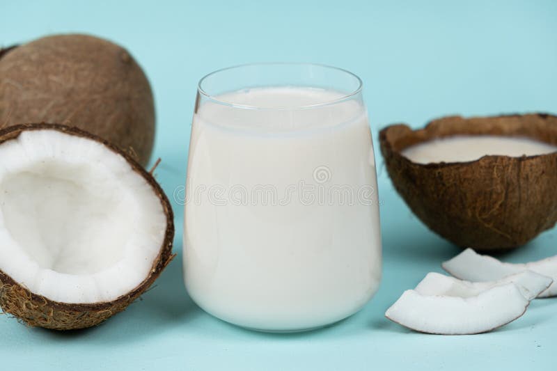 Healthy Vegan Coconut Milk in a Glass and Coconut Shell on a Blue ...