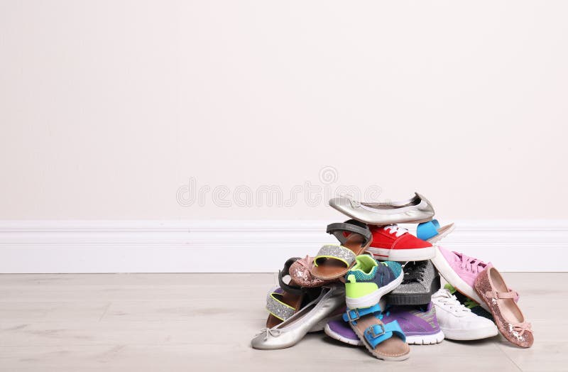 Heap of Different Shoes on Floor Against Light Wall Stock Photo - Image ...