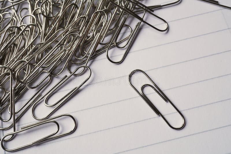 Heap of Metal Paper Clips on White Lined Paper Notepad As a Symbol of ...