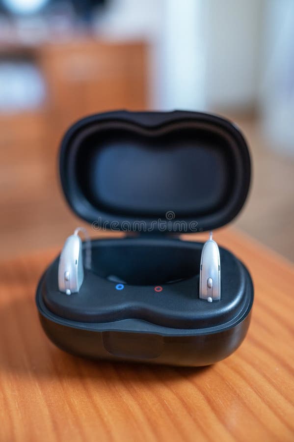 Hearing Aid Devices Charging in Modern Black Case on Wooden Table Stock ...