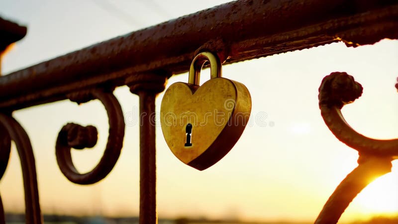Golden Heart Shaped Padlock Hanging on a Bridge Railing at Sunset Stock ...