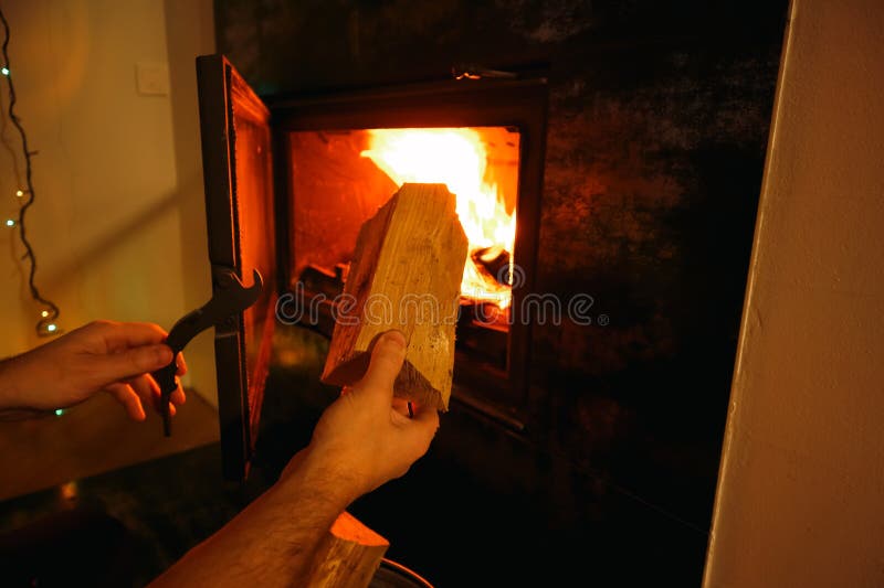 Heating Home Concept. Mans Hand Loading Firewood into Burning Fireplace ...