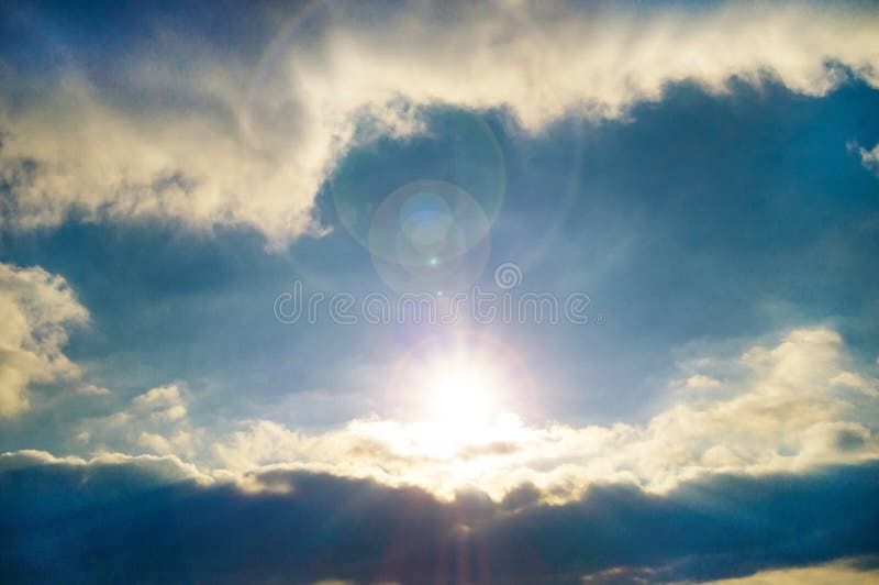 Shining Rays of the Sun Against a White Cloud and Blue Sky Stock Photo ...