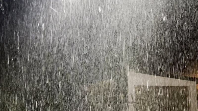 Heavy Rainfall Captured in Motion with Raindrops Falling Intensely Under Soft Light, Creating a ...