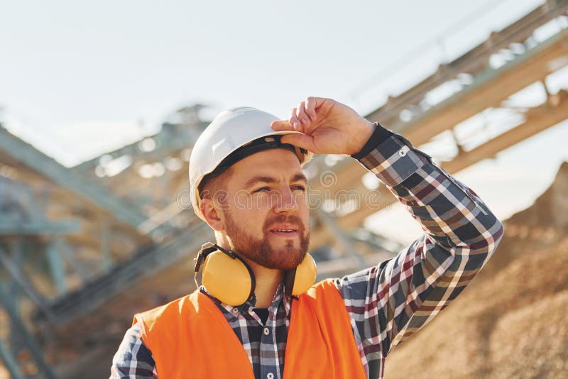 Heavy Transport Behind. Construction Worker in Uniform is on the Quarry ...