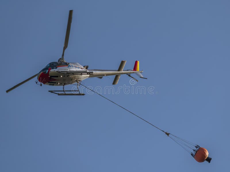Helicopter in Flight with Winch and Water Container, in Action To Put ...