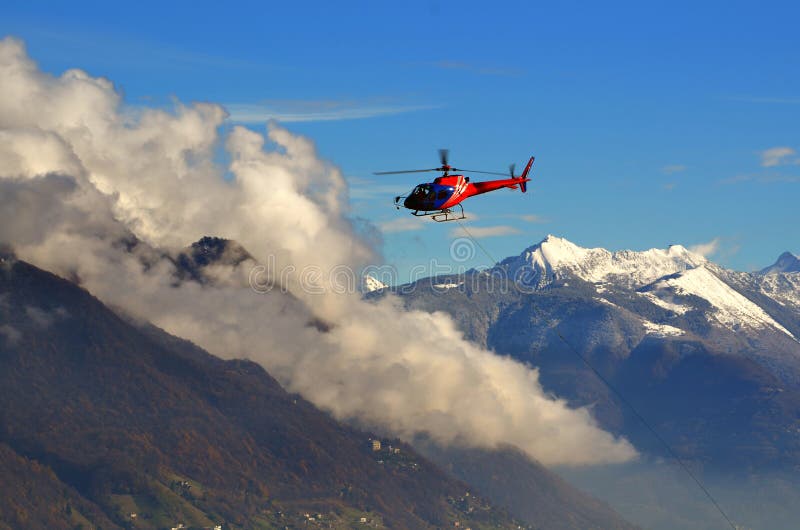 Helicopter Flying among the Clouds Above the Snow-capped Mountains ...