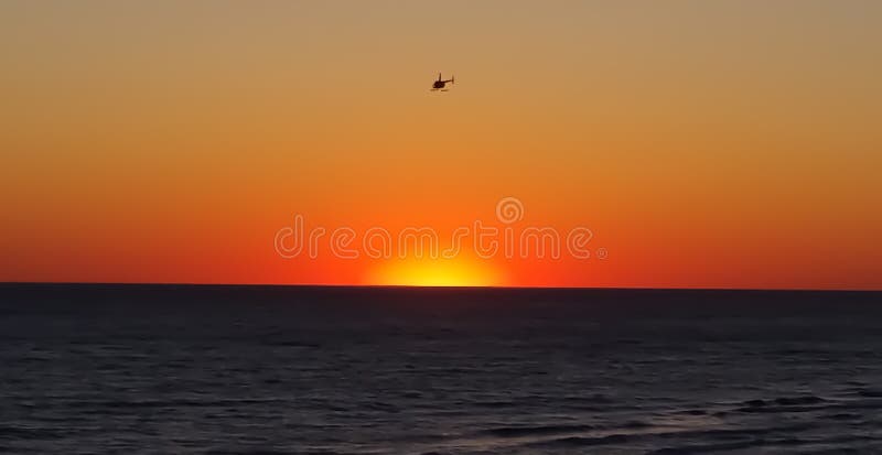 Helicopter Flying in the Sunset Over Ocean Stock Image - Image of beach ...