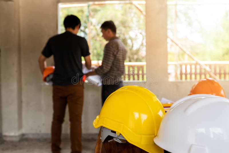 Helmets on Desk in Front of Engineer or Architect Discussing with ...