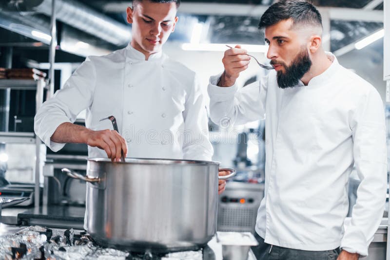 With Help from Other Employee. Chef in White Uniform Cooking Food at ...
