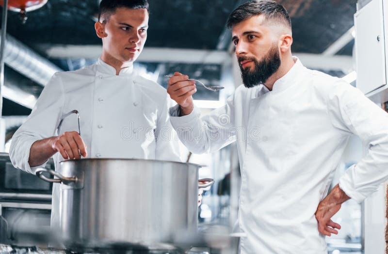 With Help from Other Employee. Chef in White Uniform Cooking Food at ...