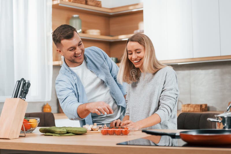 Helping Each Other. Couple Preparing Food at Home on the Modern Kitchen ...