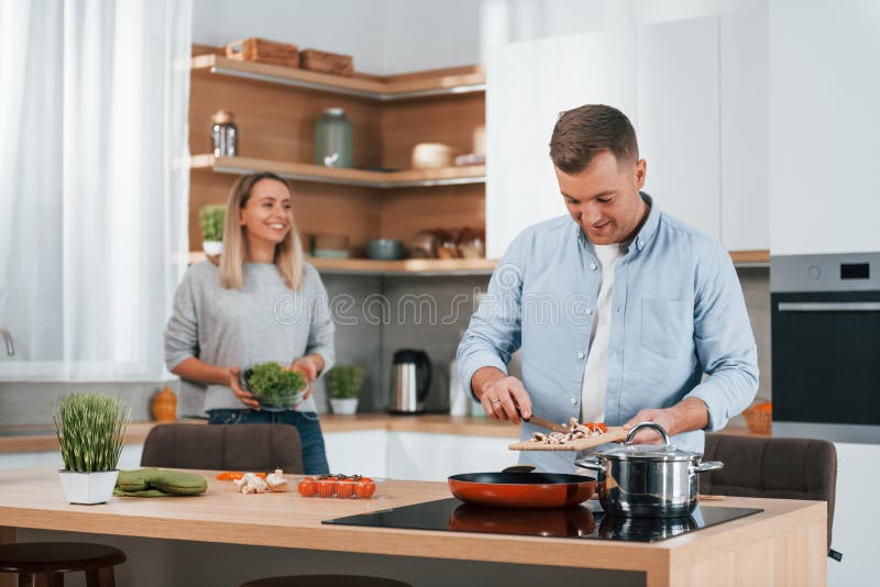 Helping Each Other. Couple Preparing Food at Home on the Modern Kitchen ...