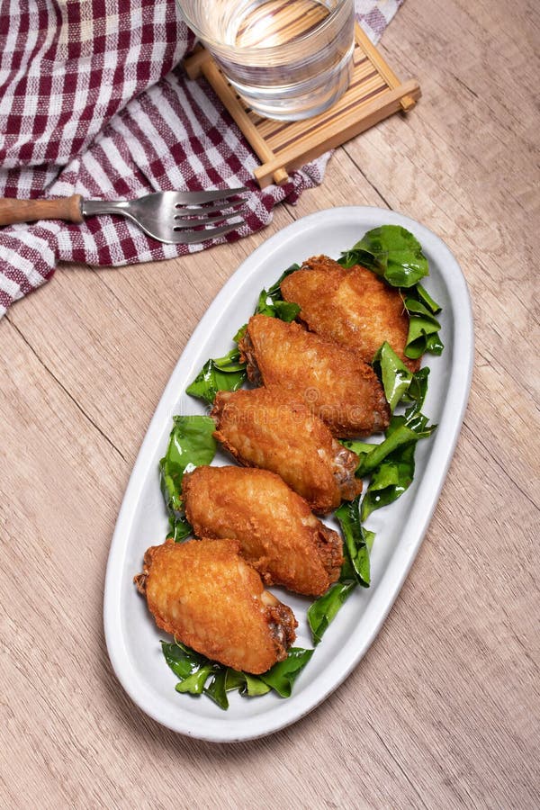 Herb Fried Chicken Wings in White Plate on Wooden Floor Stock Photo ...